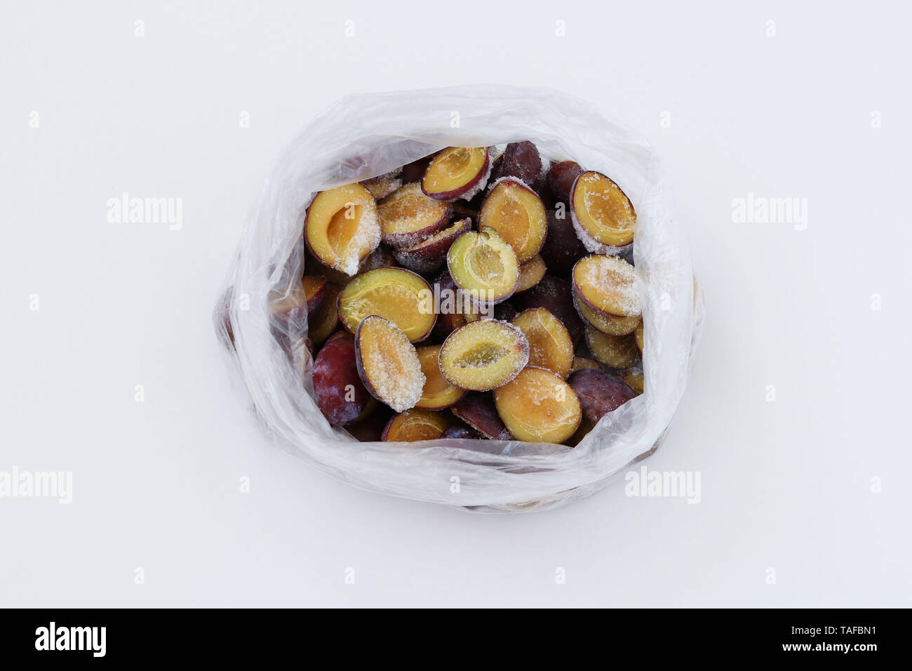 Frozen plums in a transparent package located on a white background ...