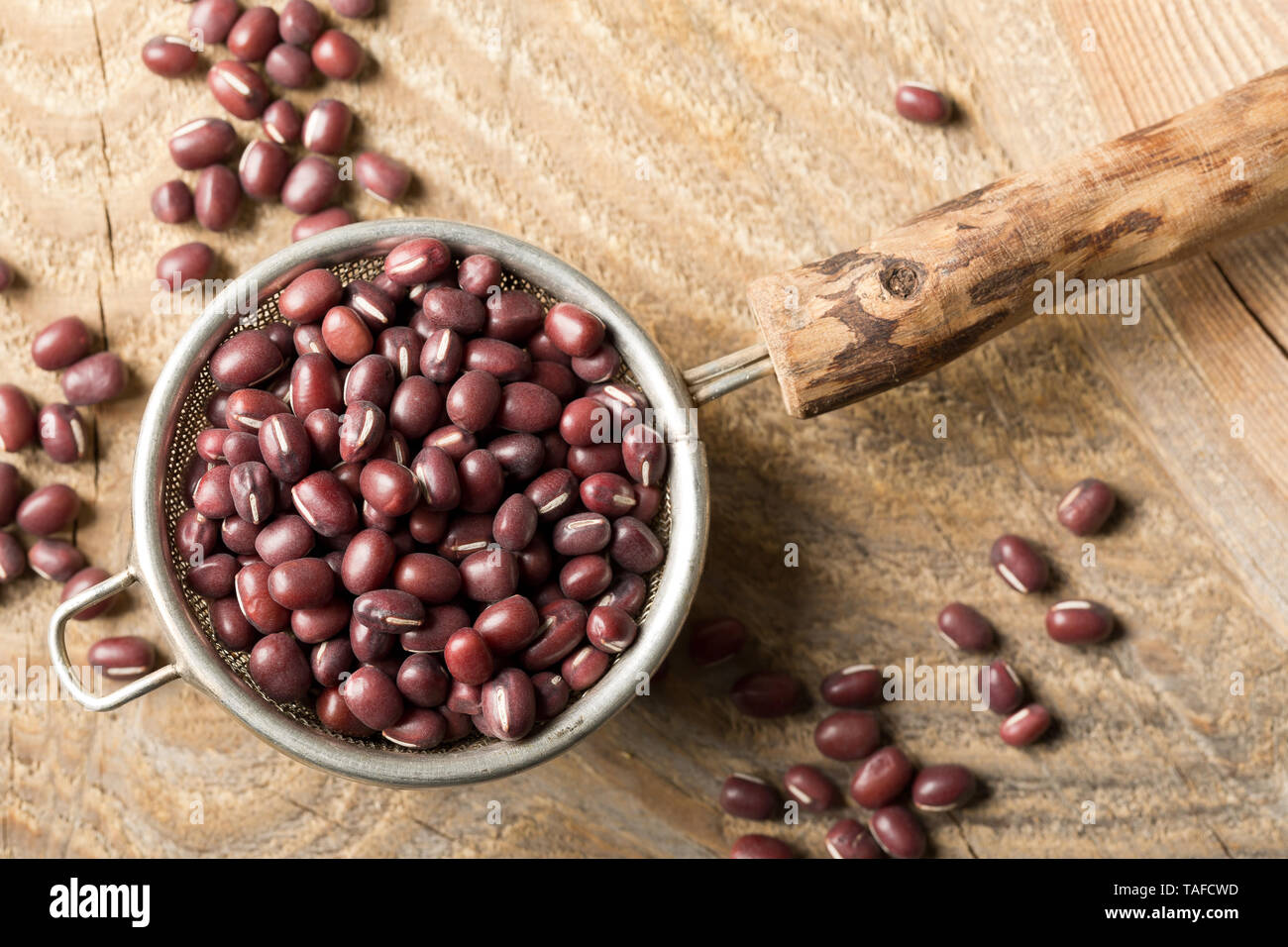 Raw, uncooked, dried adzuki (red mung) beans in small sieve on rustic ...
