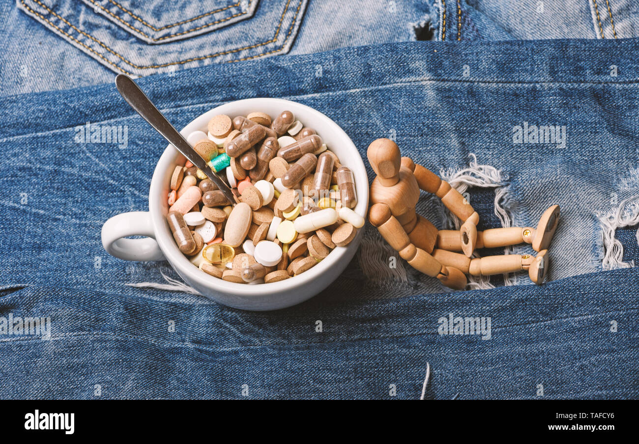 Medicines dose. Wooden human dummy near cup full pills and tablets ...
