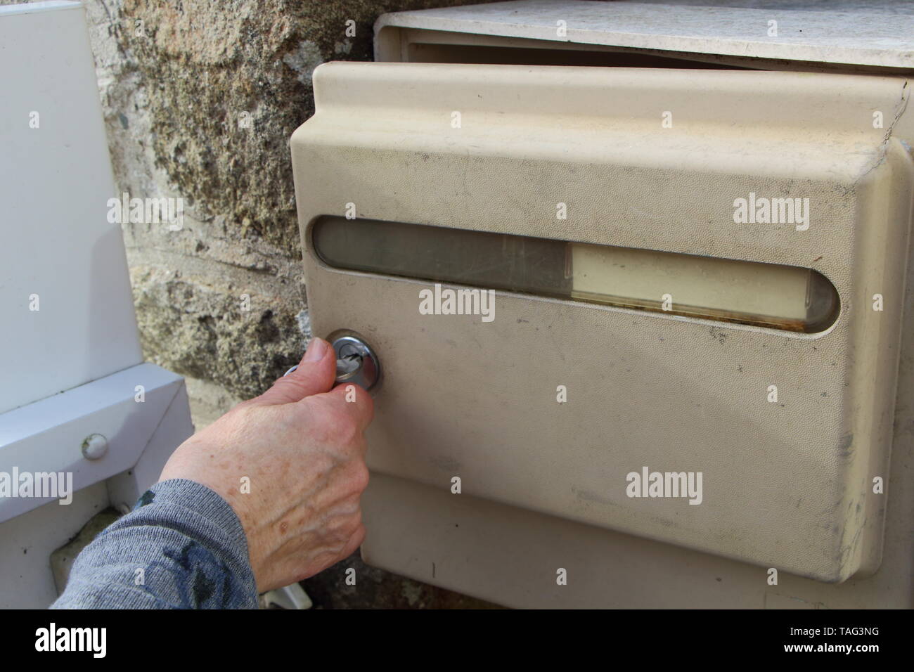 Hand of a woman opening a mailbox with a key Stock Photo - Alamy