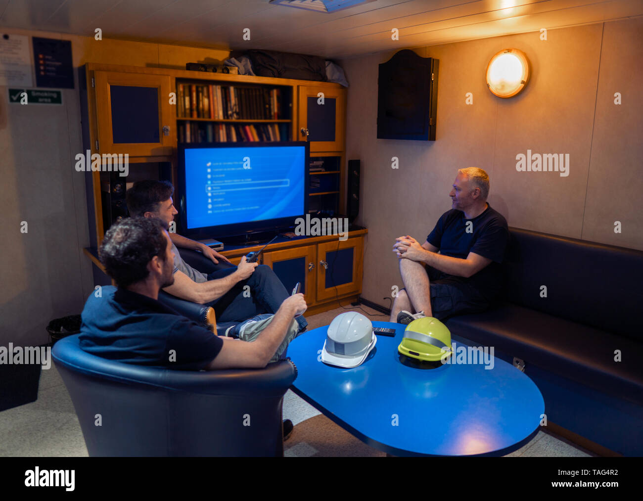 Happy team of ship officers watch TV onboard of vessel Stock Photo - Alamy
