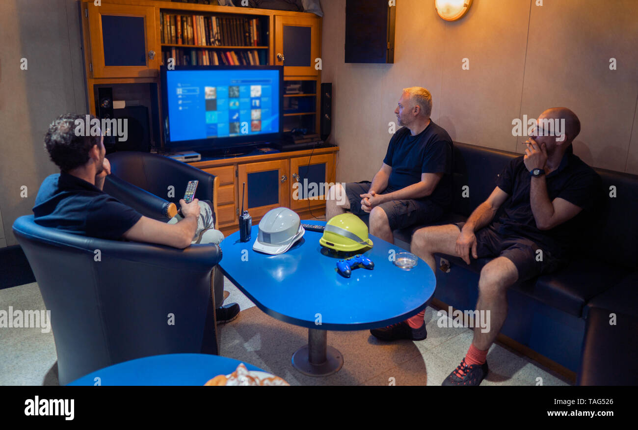 Happy team of ship officers watch TV onboard of vessel Stock Photo - Alamy