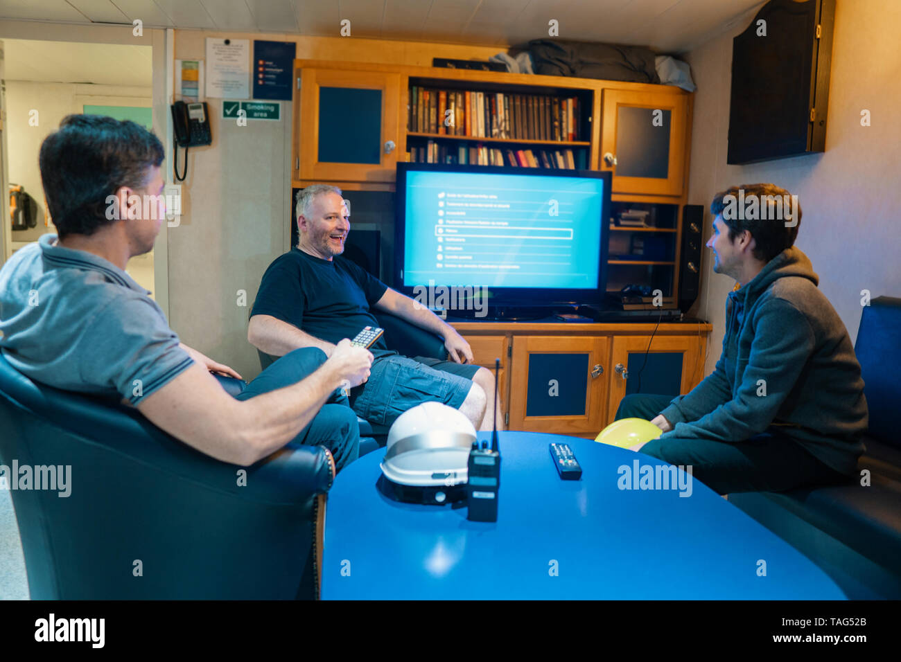 Happy team of ship officers watch TV onboard of vessel Stock Photo - Alamy
