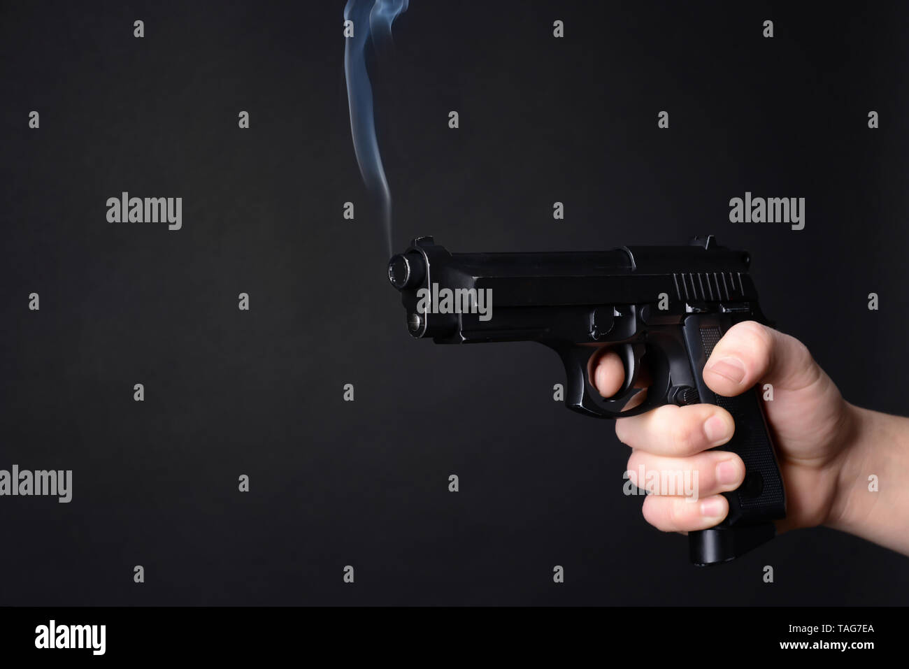 Male hand with smoking gun on dark background Stock Photo - Alamy