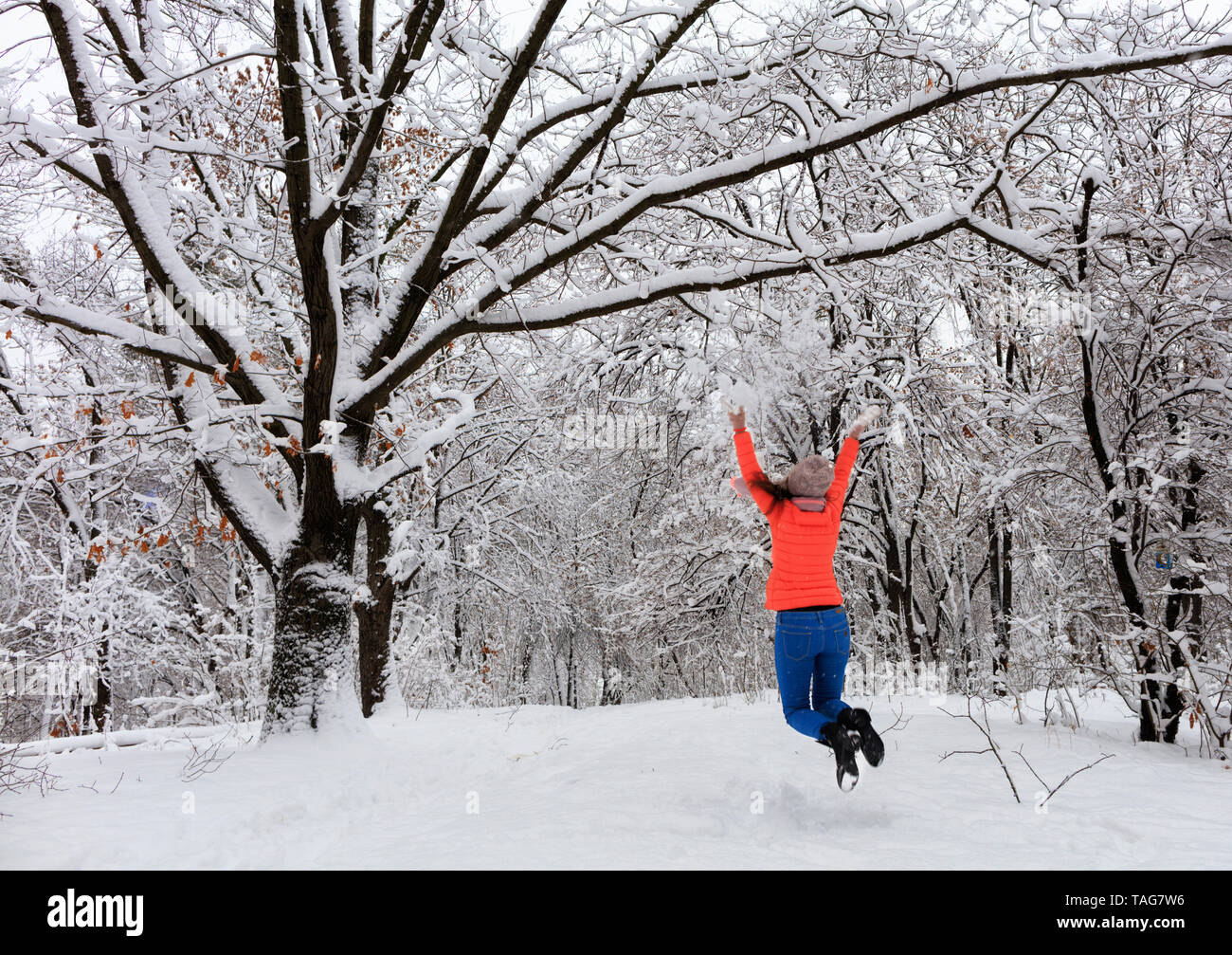 A young beautiful girl in a bright coral jacket and blue jeans in the ...