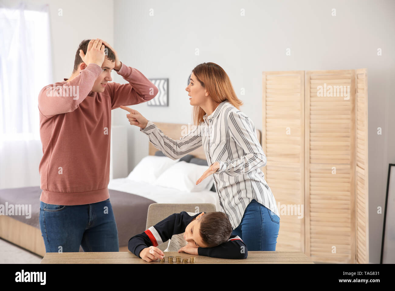 Sad little boy with coins and his quarreling parents at home. Concept ...