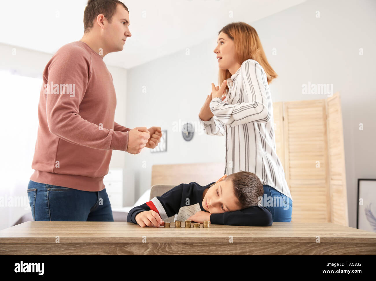 Sad little boy with coins and his quarreling parents at home. Concept ...