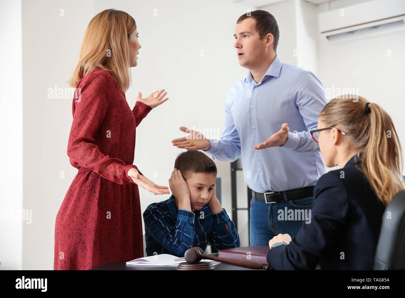 Sad little boy with his quarreling parents in lawyer's office. Concept ...