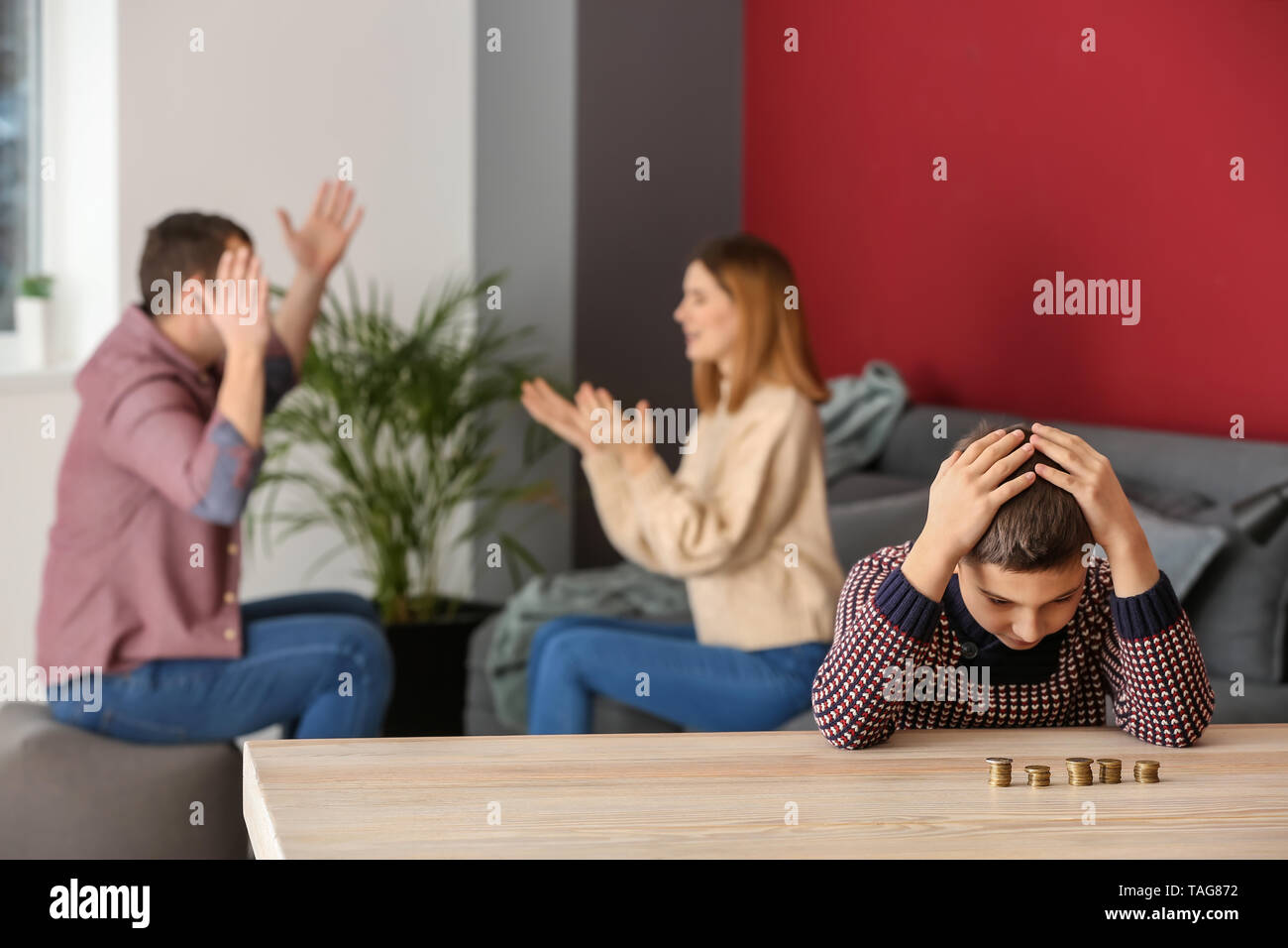 Sad little boy with coins and his quarreling parents at home. Concept ...