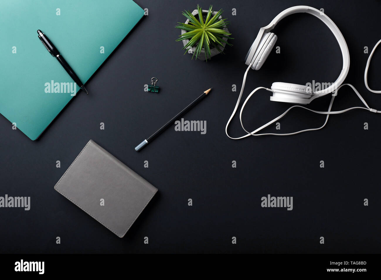 Stylish workplace with stationery and headphones on dark background ...