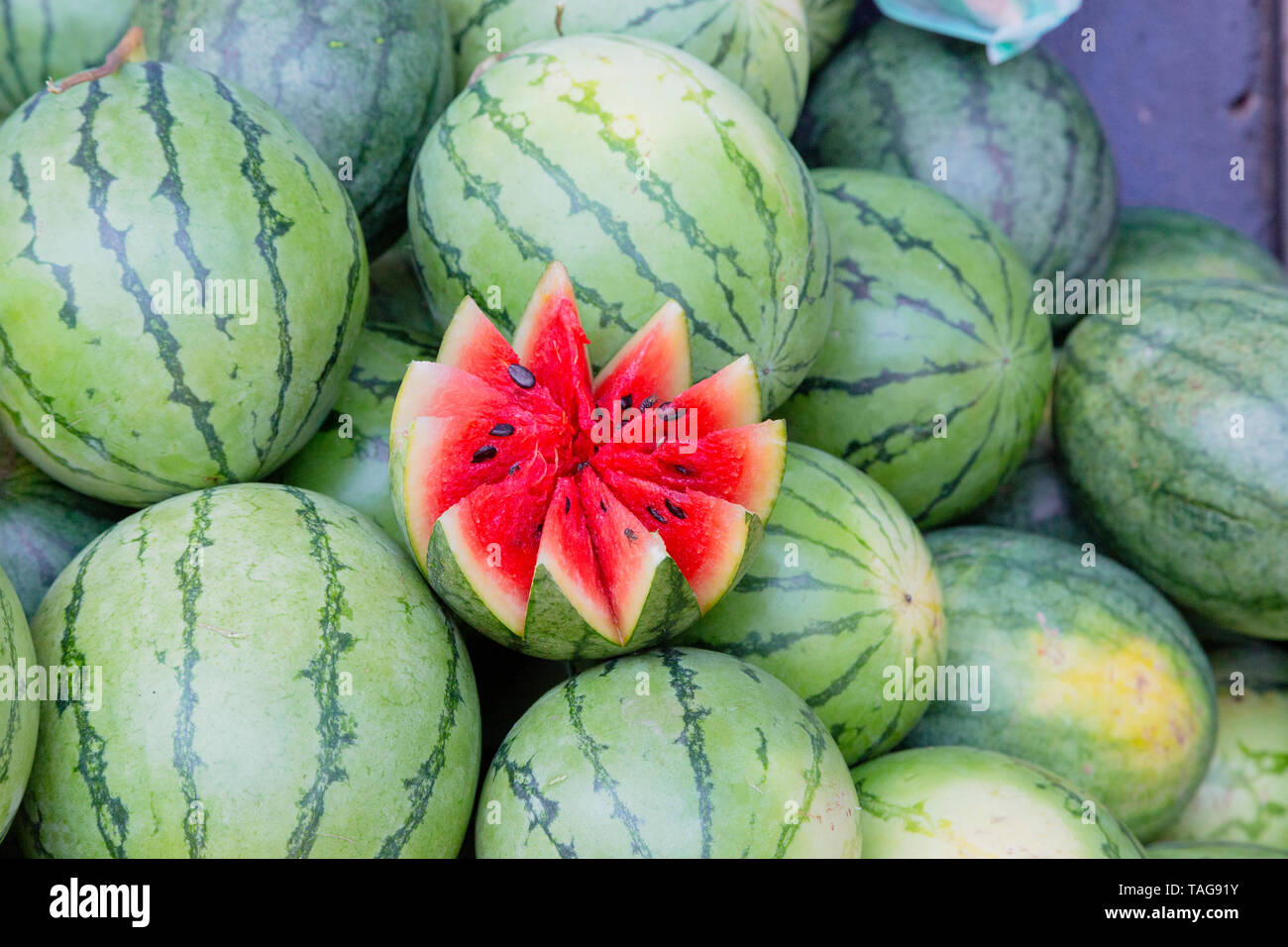Watermelon on display for sale at outdoor market with some cut open ...