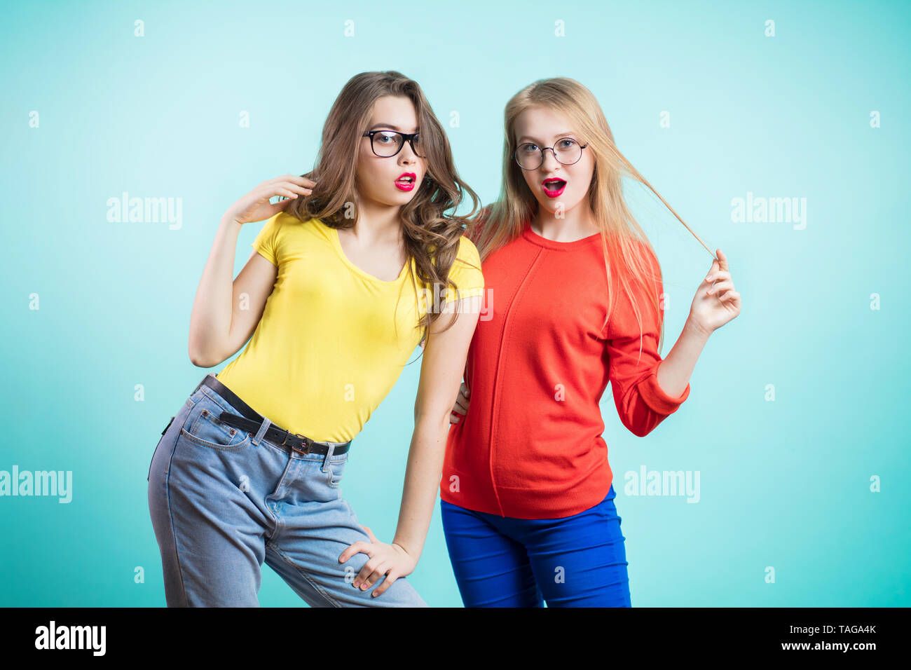 Portrait of the surprised and shocked two women on a blue background ...
