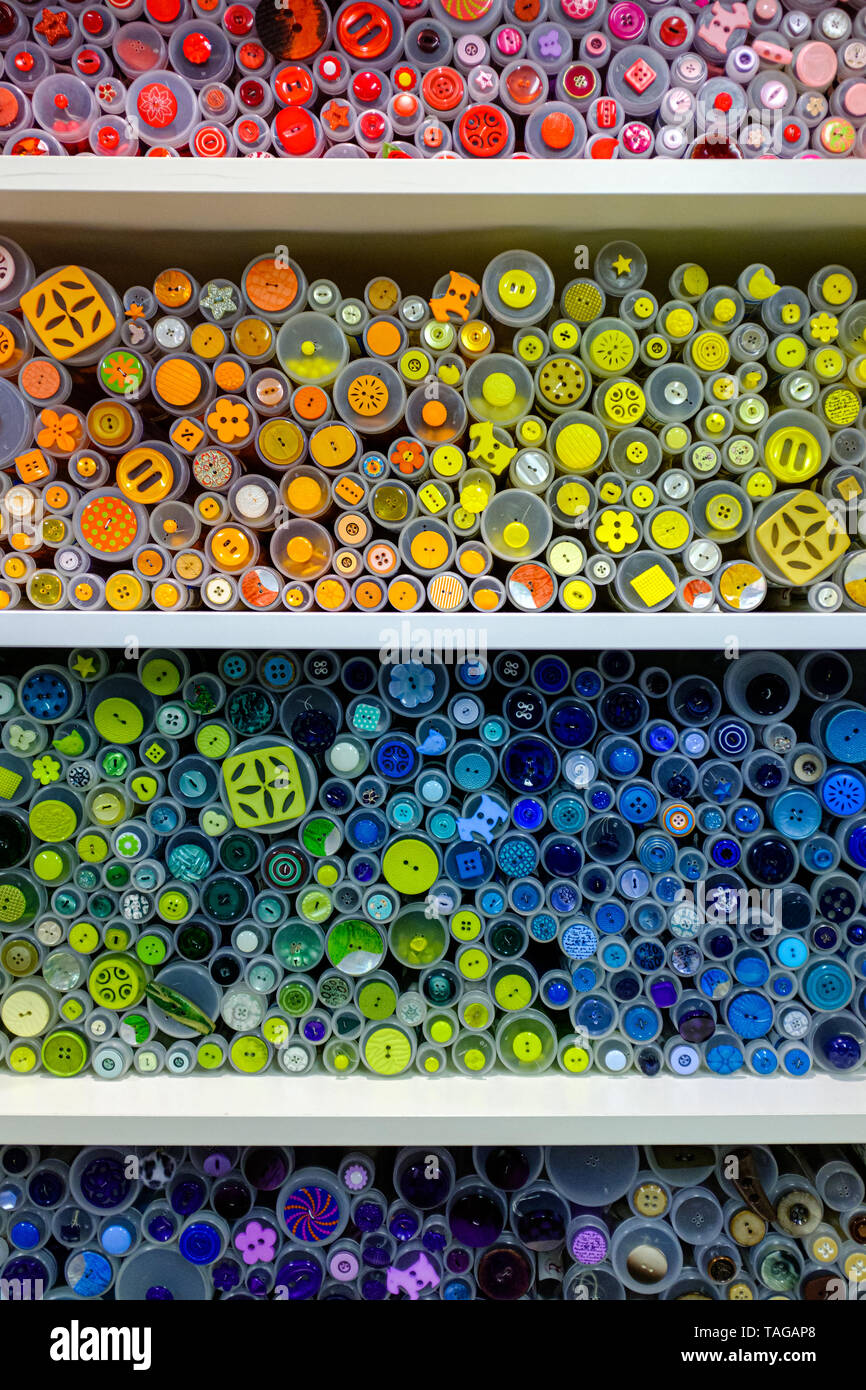 Colourful rainbow effect of buttons in tubes for sale in a craft store ...