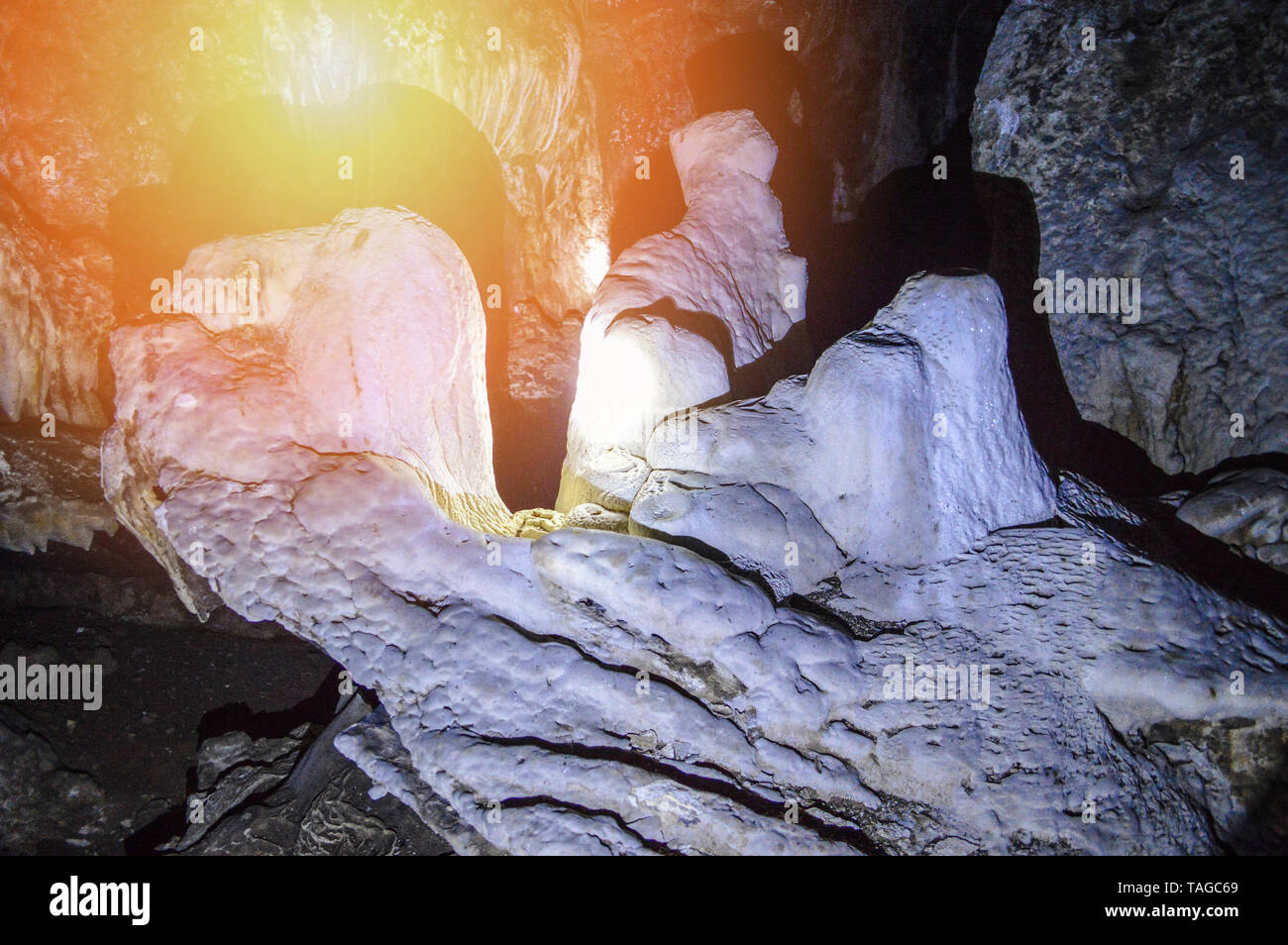 Stalagmite and stalactite stone in dark cave with light from flashlight ...