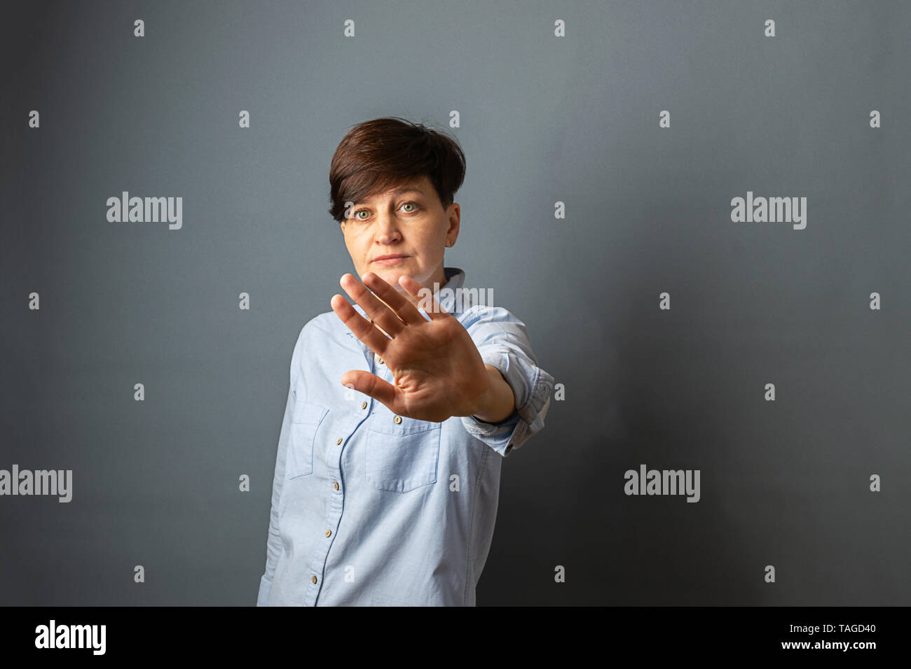 Portrait of a young woman with short haircut on a gray blank background ...