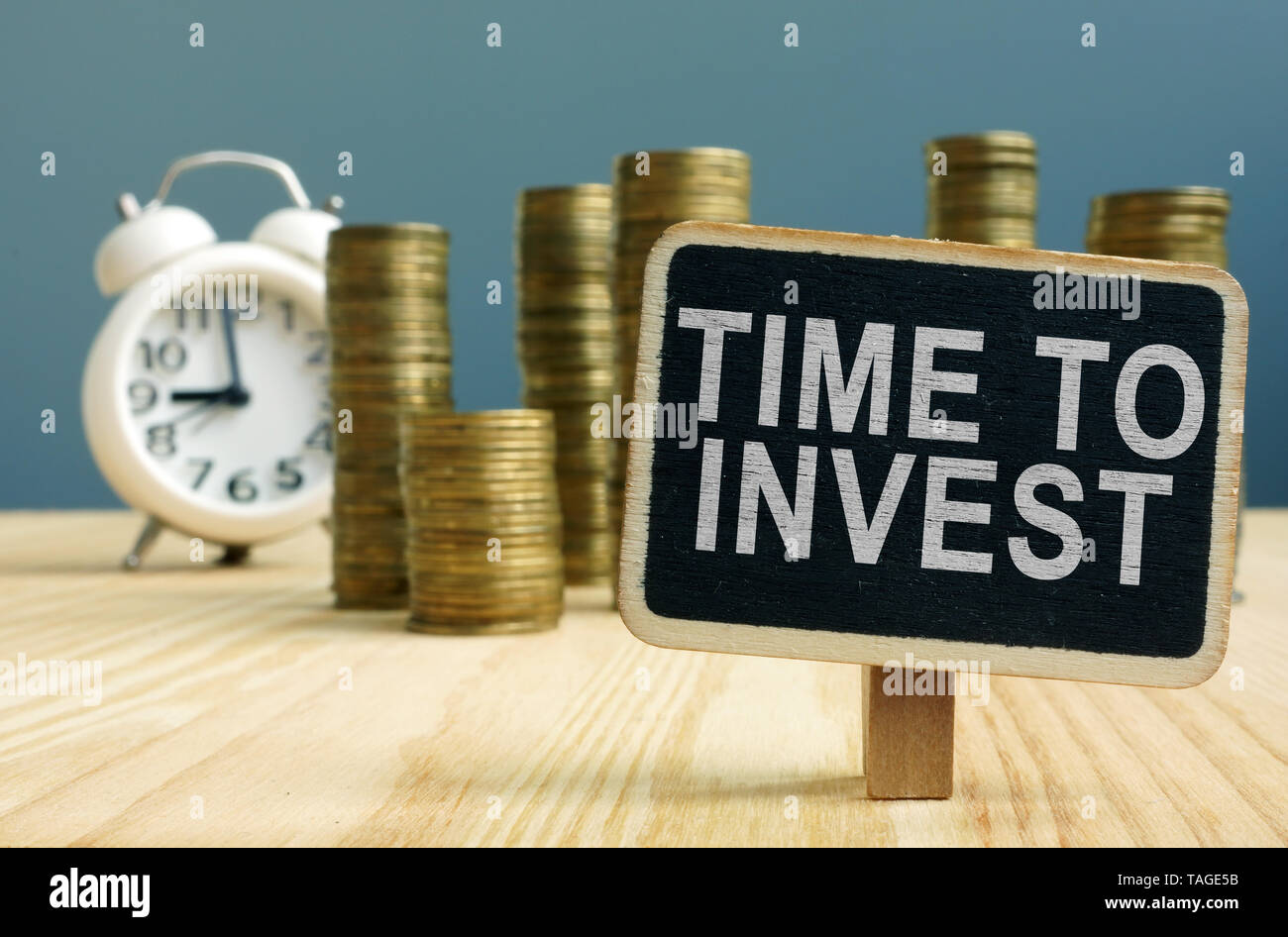 Time to invest concept. Stacks of coins and alarm clock Stock Photo - Alamy
