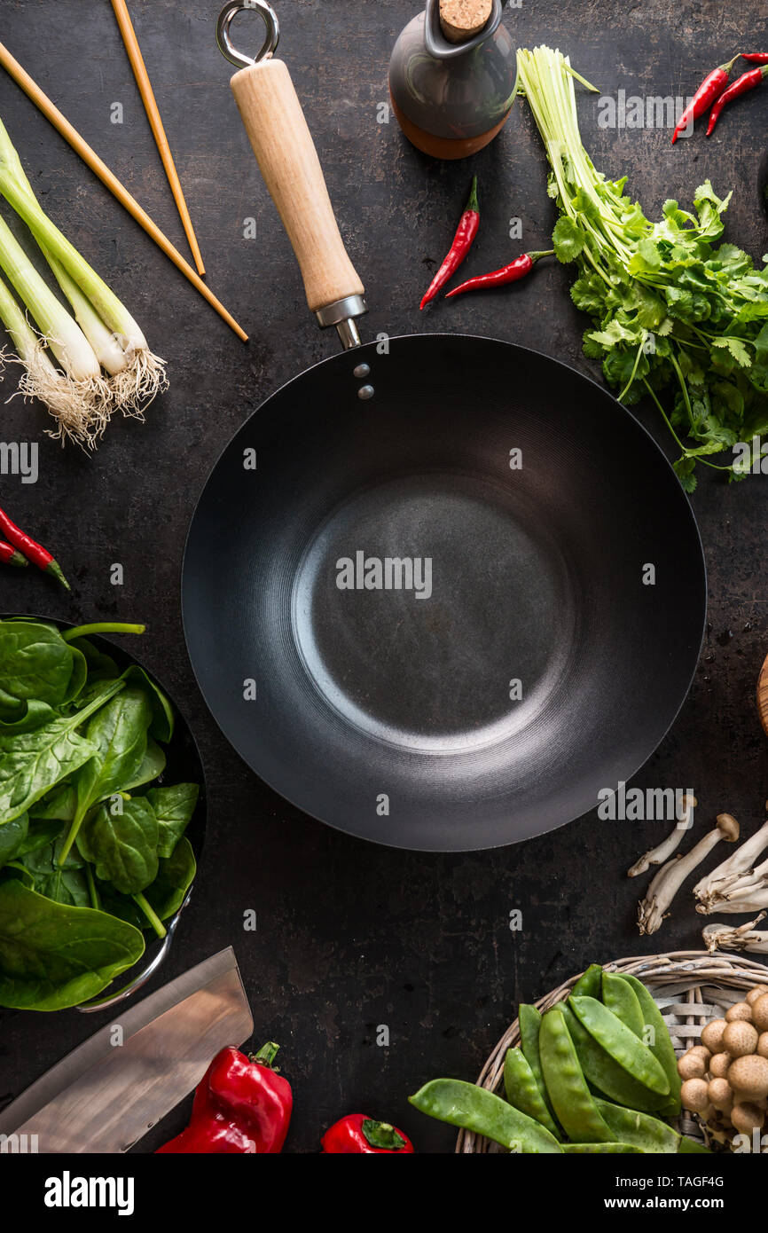 Empty wok pan on kitchen table with chopsticks and vegetarian Asian ...