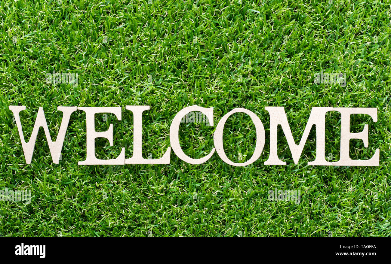 Wood alphabet in word welcome on artificial green grass background ...