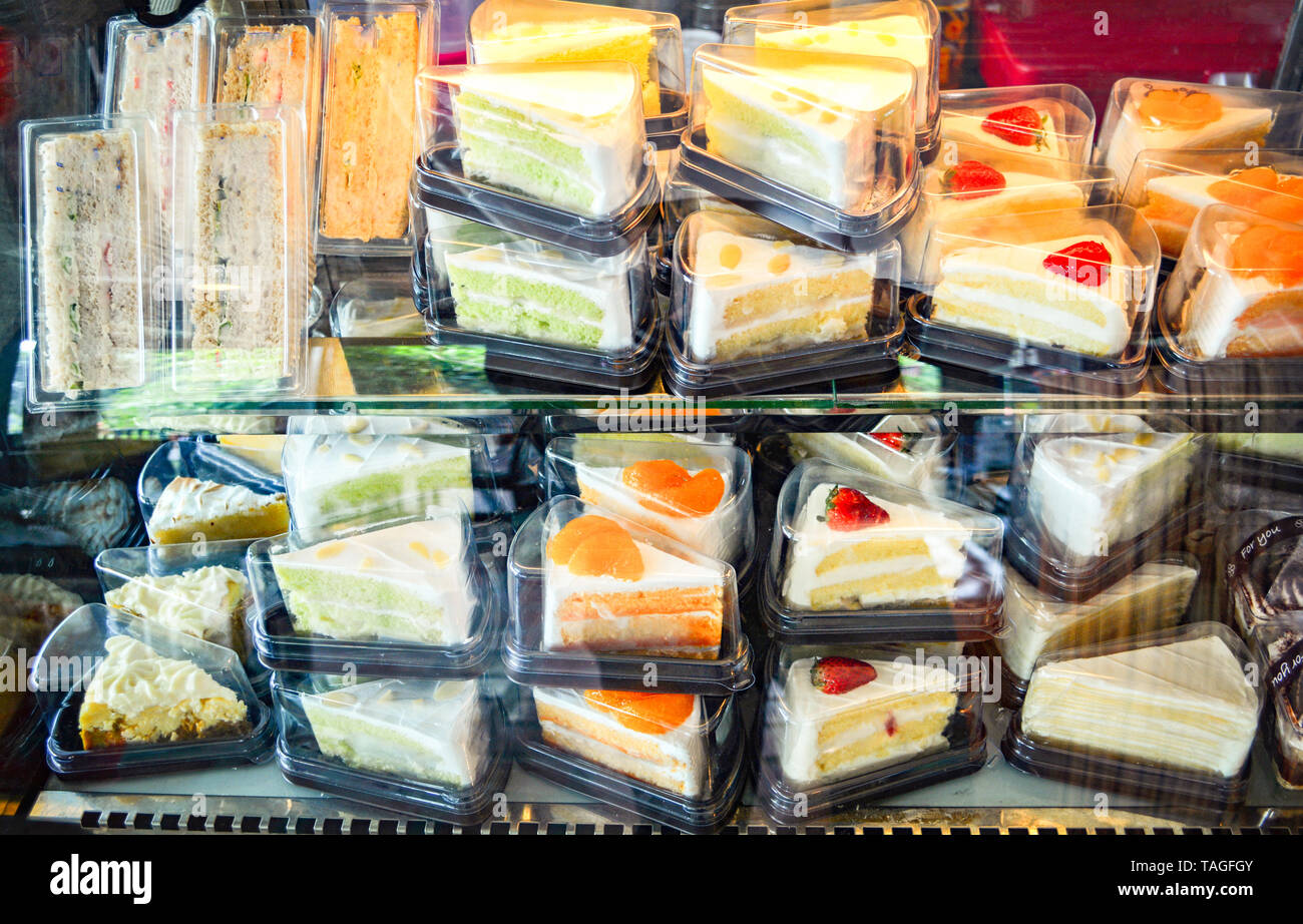 Cake slice in plastic box in glass display showcase at bakery and cake ...