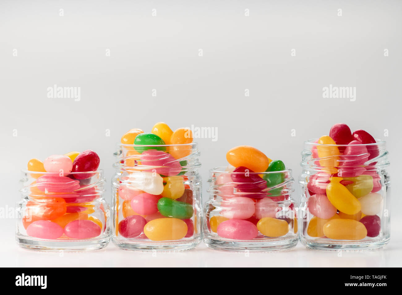 Jelly beans in small glass jars on white background Stock Photo - Alamy
