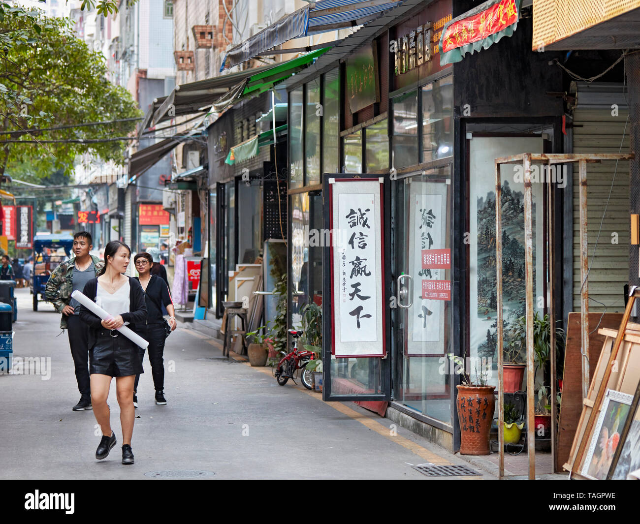 People passing by a local art gallery in Dafen Oil Painting Village ...