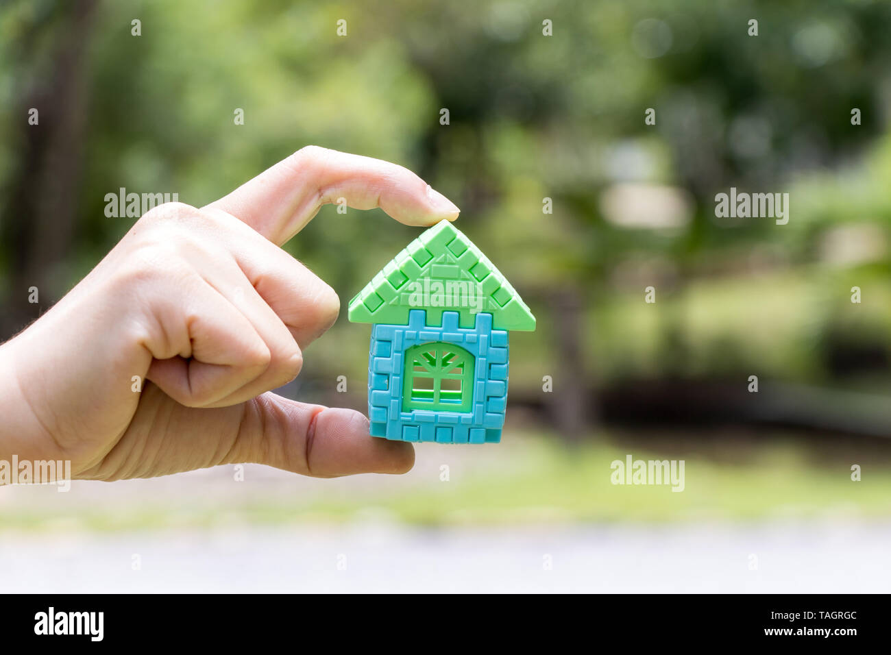 Woman hand hold home block model with blur green background (Concept ...