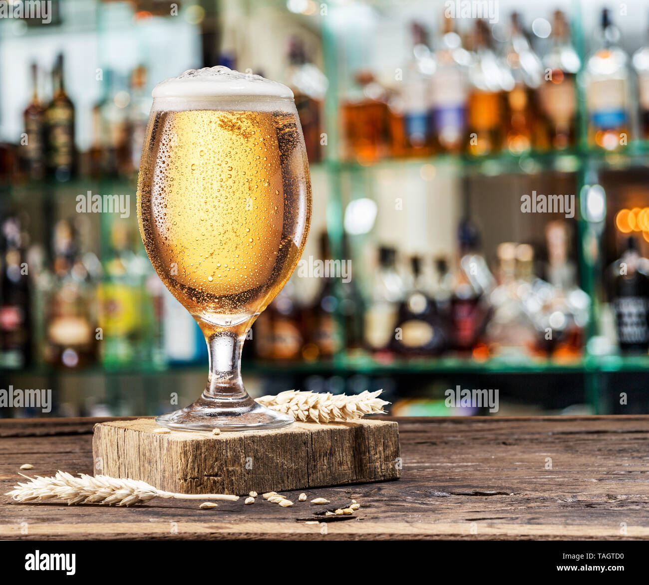Chilled glass of light beer on the bar counter. Blurred bar background ...