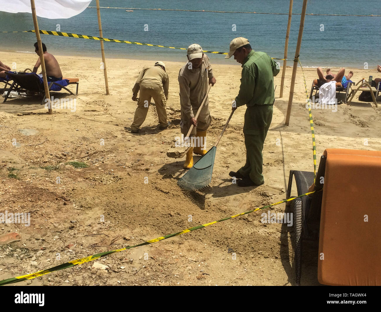 Workmen replacing sand after heavy rain at a tourist beach Stock Photo ...