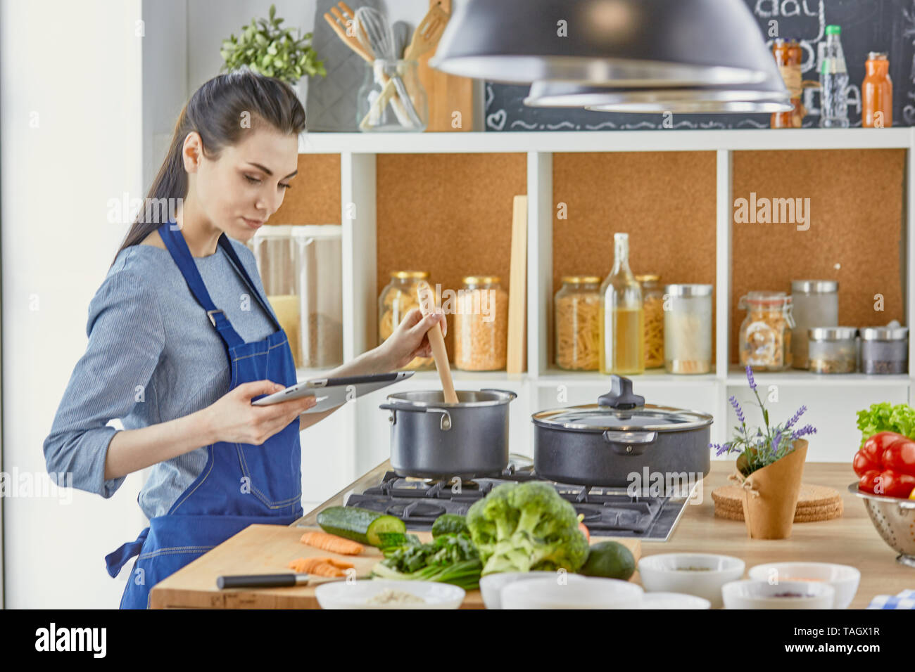 Happy woman looking recipe tablet kitchen reading cooking Stock Photo ...
