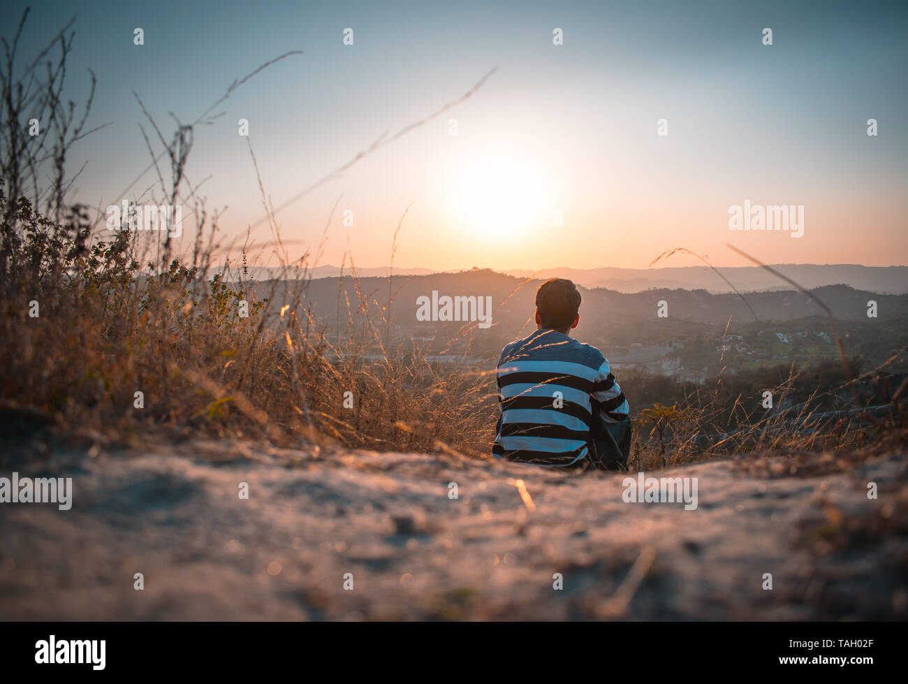 Man sitting peacefully and watching a sunset.Orange sunset glow on a ...