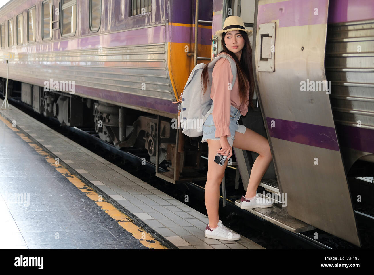 young woman tourist traveler stepping up to train on railway at train ...