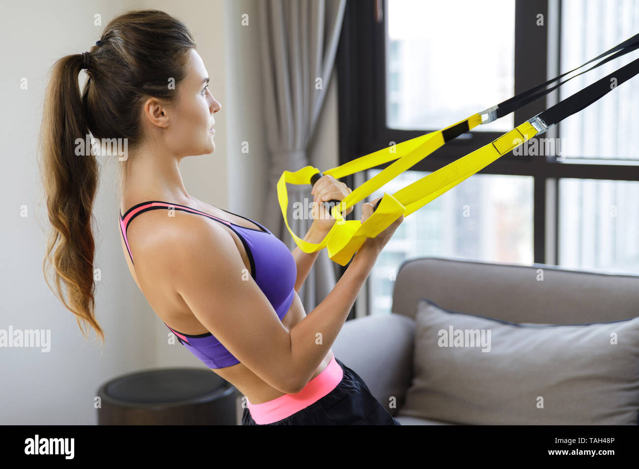 Woman during her fitness workout at home with resistance suspension ...