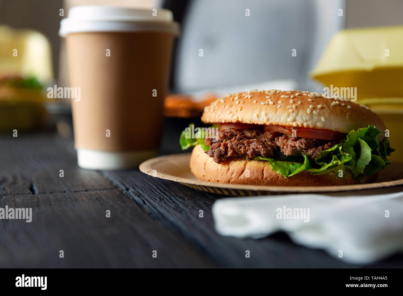 Hamburger on a paper plate on the wooden background. Food delivery and ...