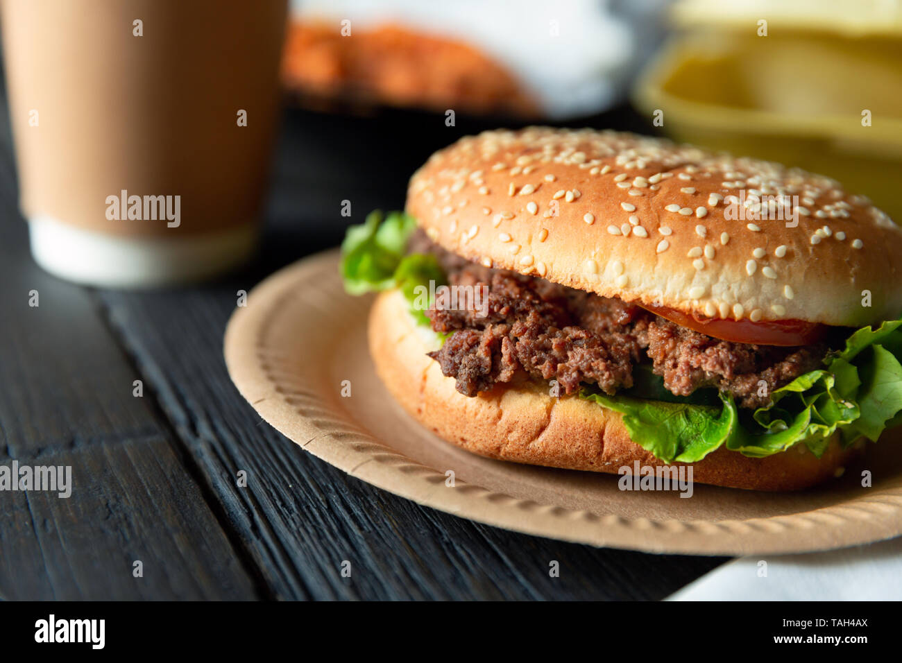 Hamburger on a paper plate on the wooden background. Food delivery and ...