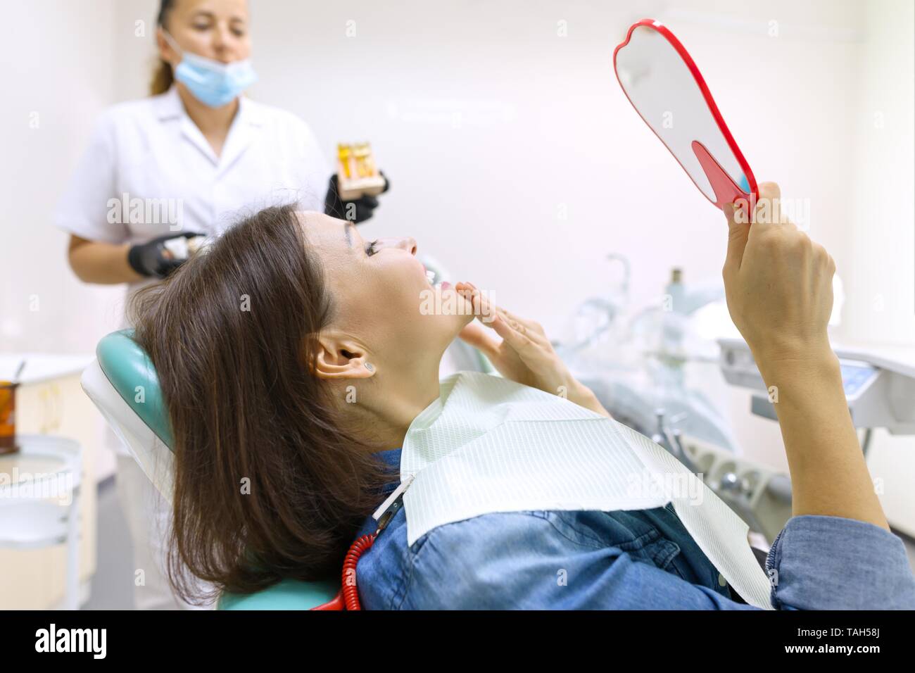 Process of dental treatment. Female patient looking at her teeth in ...