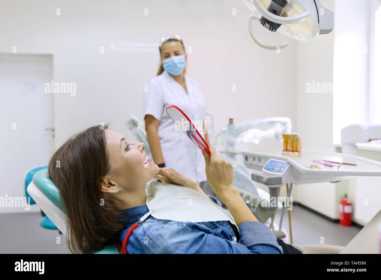Process of dental treatment. Female patient looking at her teeth in ...