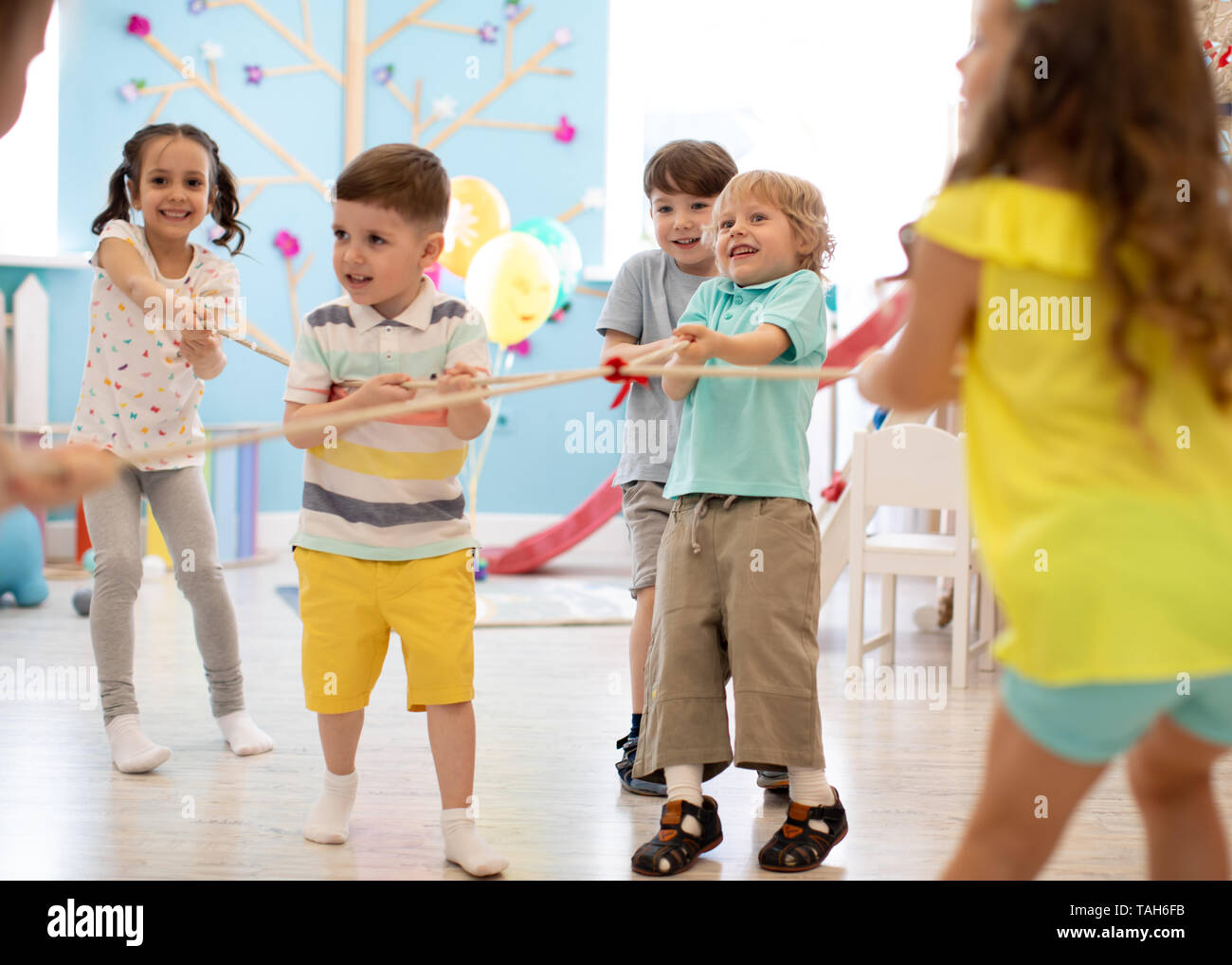 Group of kids play and pull rope together in day care. Games and ...