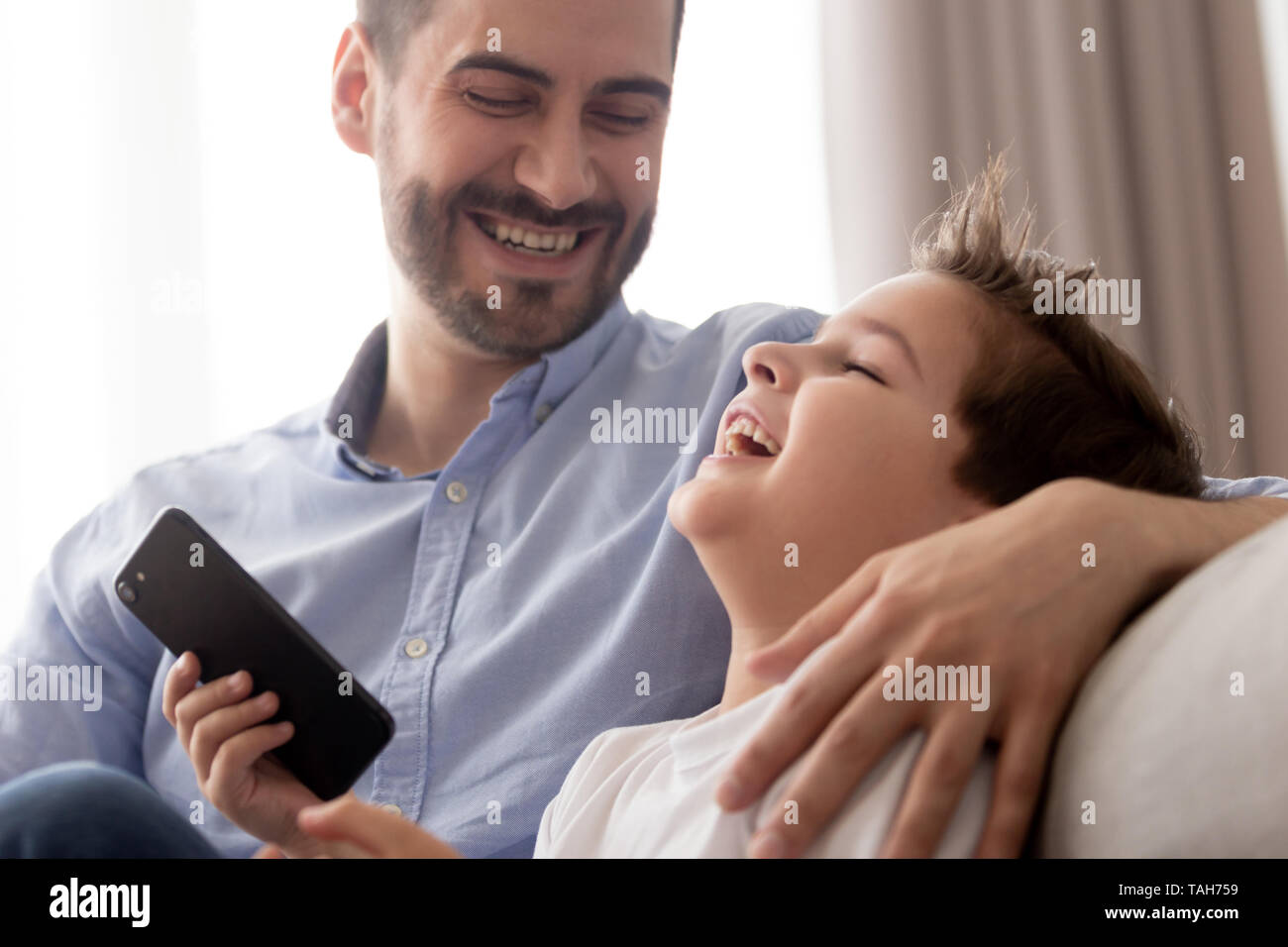 Happy dad and little son laugh using smartphone at home Stock Photo - Alamy