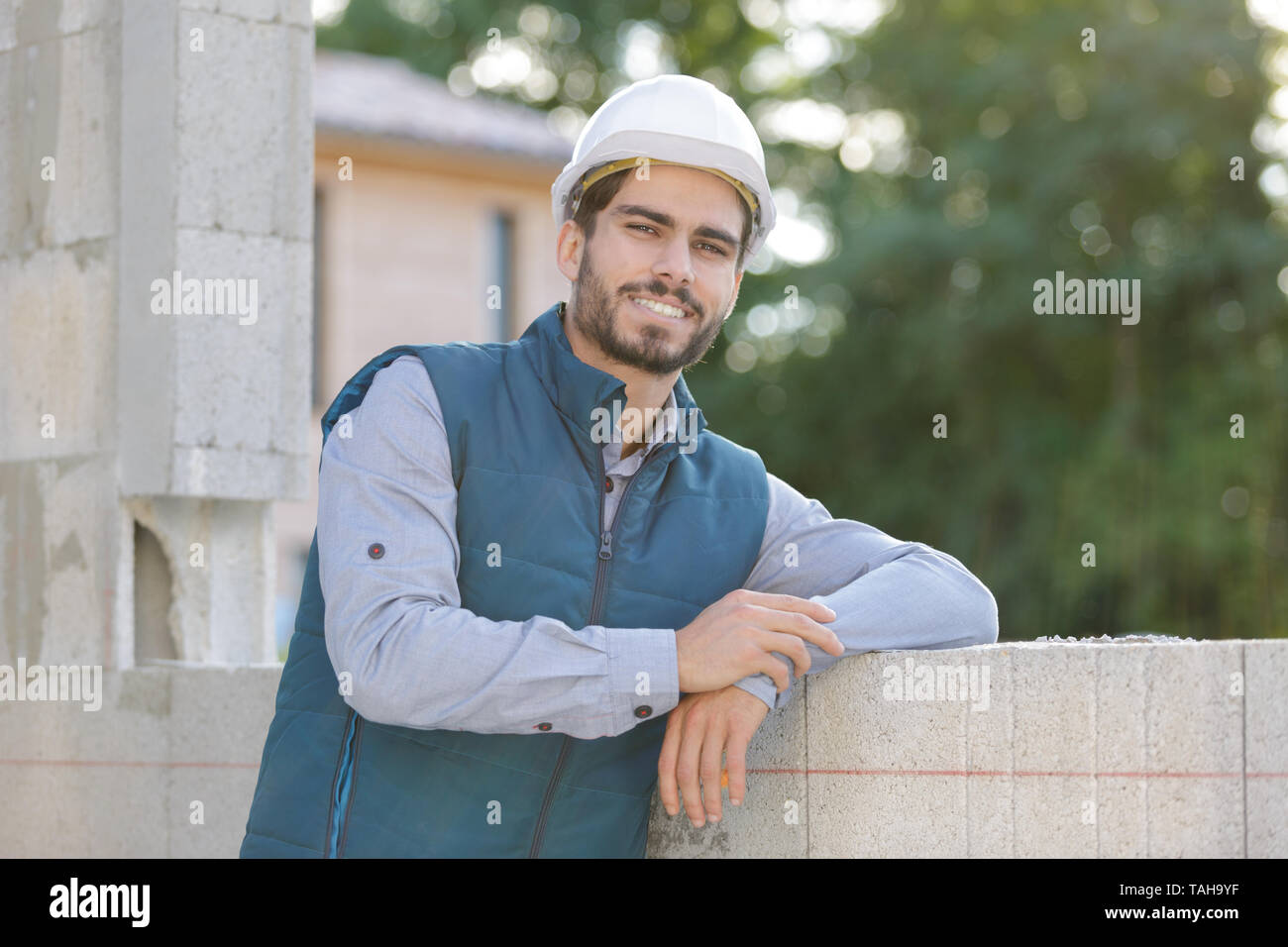 builder leaning on a concrete wall Stock Photo - Alamy