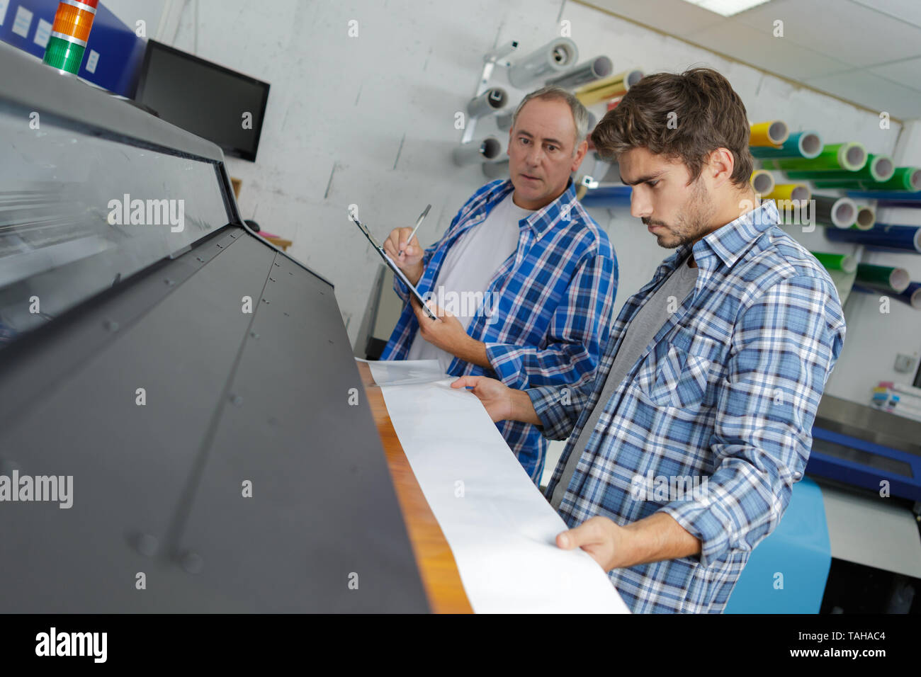 two men looking down at professional printer Stock Photo - Alamy