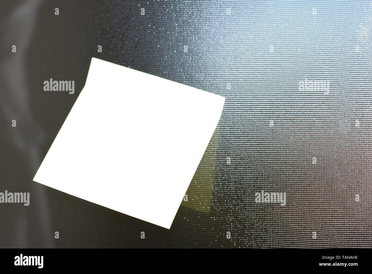 Piece of square paper use to give notation stick to textured glass ...