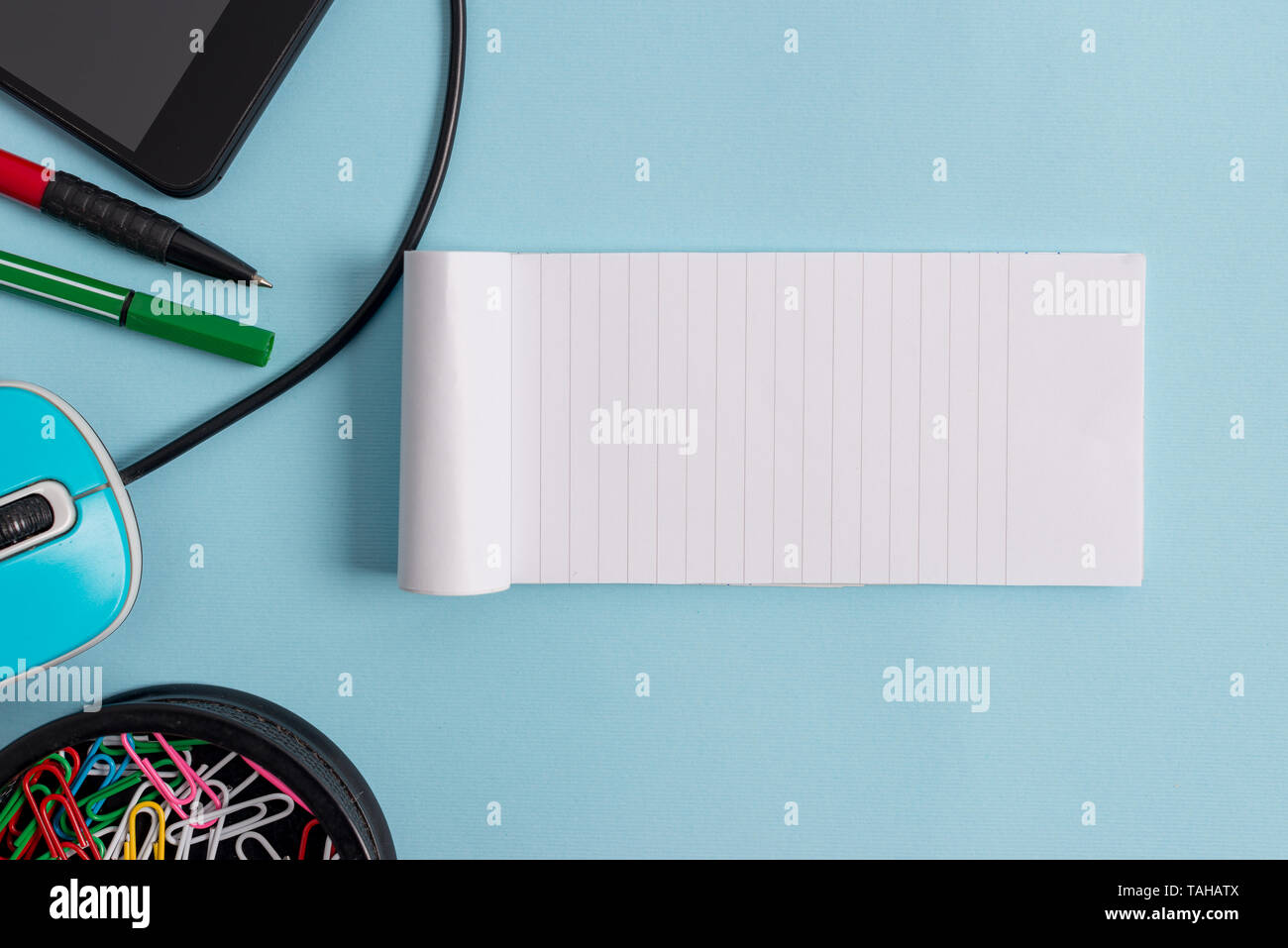Notebook and writing equipment with modern gadget above pastel backdrop ...