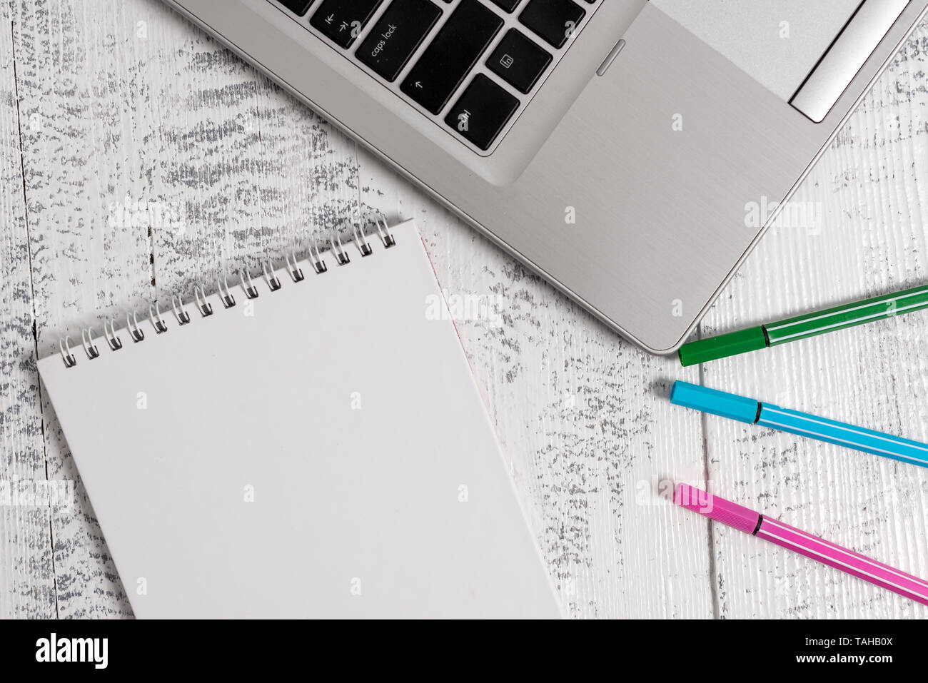 Top trendy metallic laptop blank spiral notepad pens lying wooden table ...
