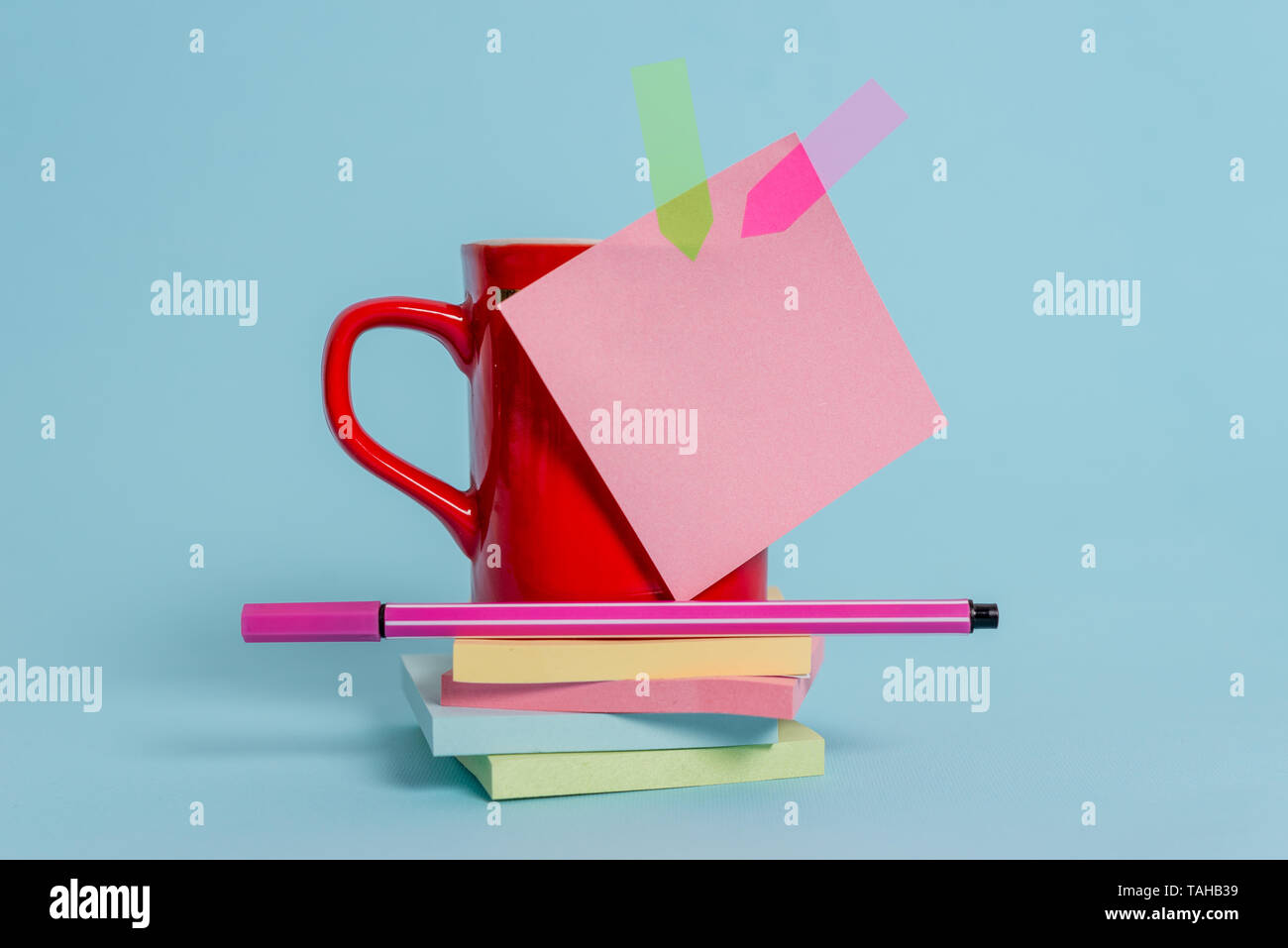Cup sticky note arrow banners stacked pads pen lying pastel background ...
