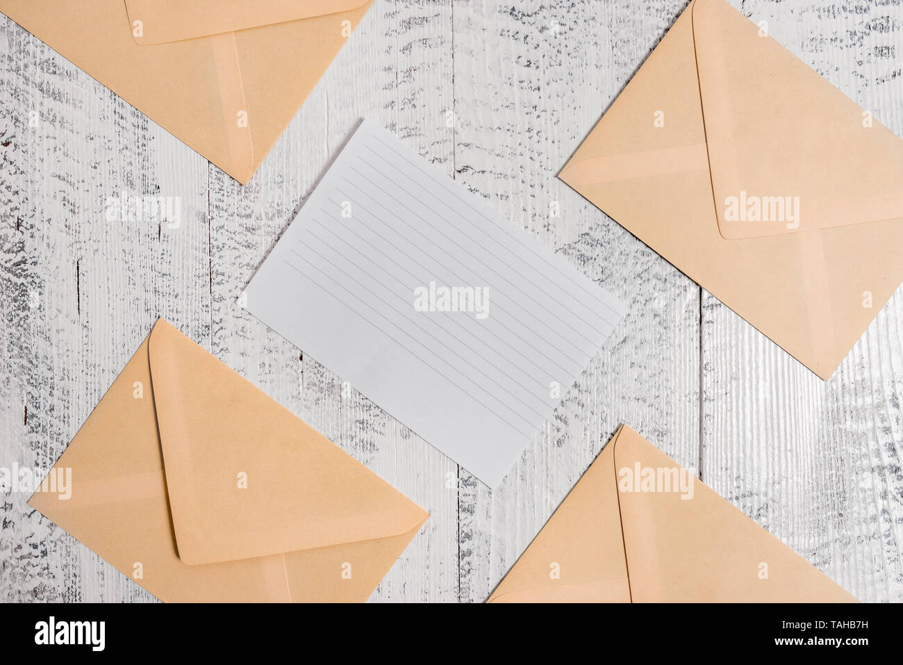 Four envelopes around ruled paper sheet old wooden vintage background ...