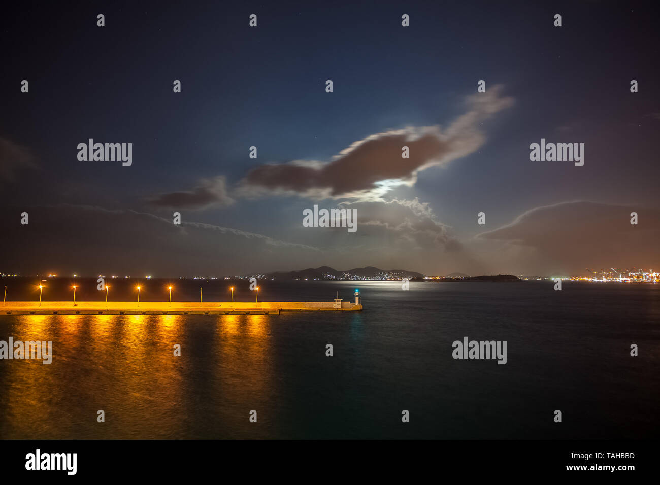 Night view of Athens Piraeus harbor with moon partially hidden by ...