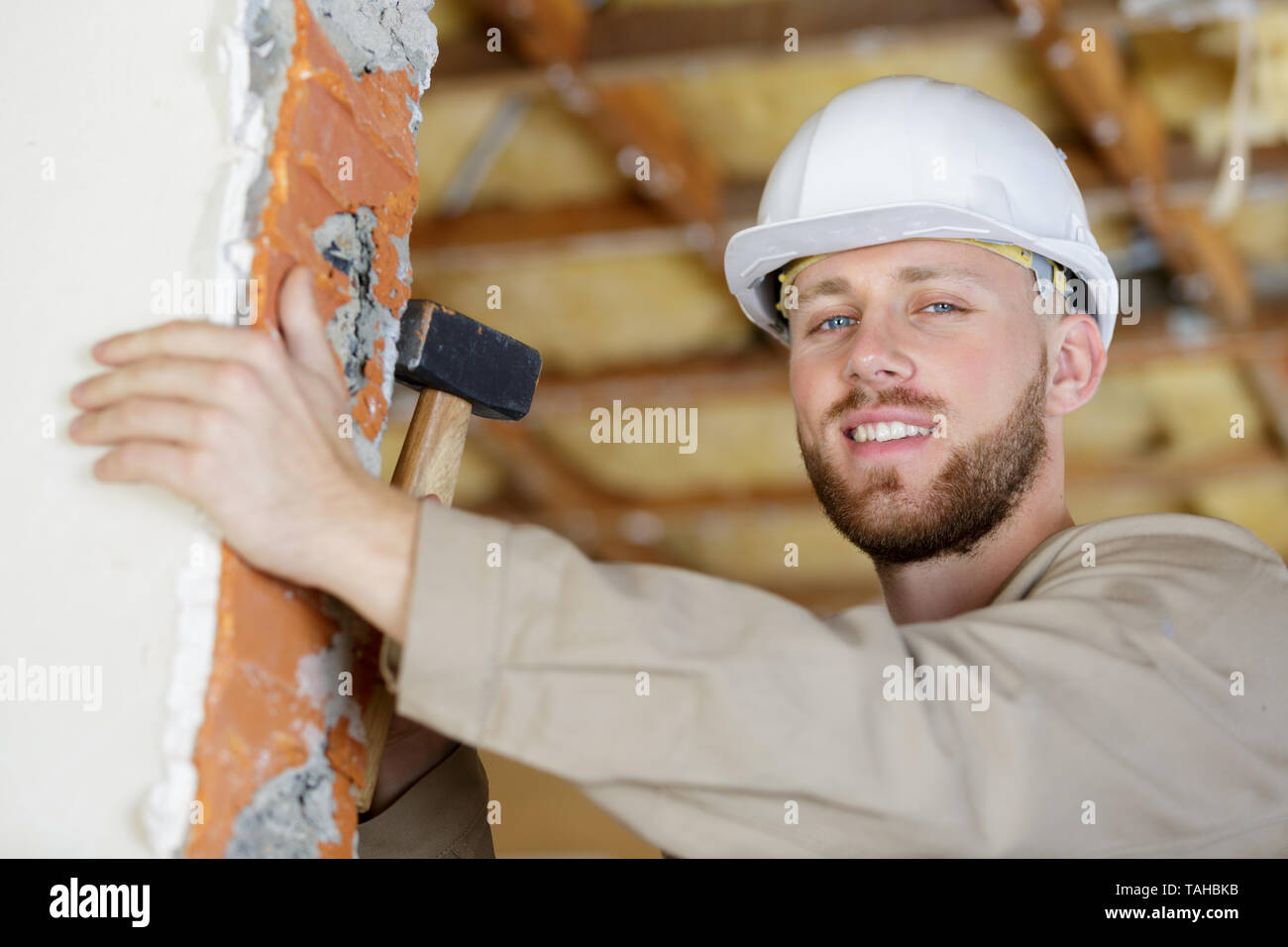 portrait of young builder using hammer on brick wall Stock Photo - Alamy