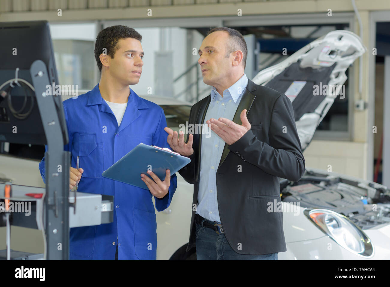 customer talking to young garage mechanic Stock Photo - Alamy