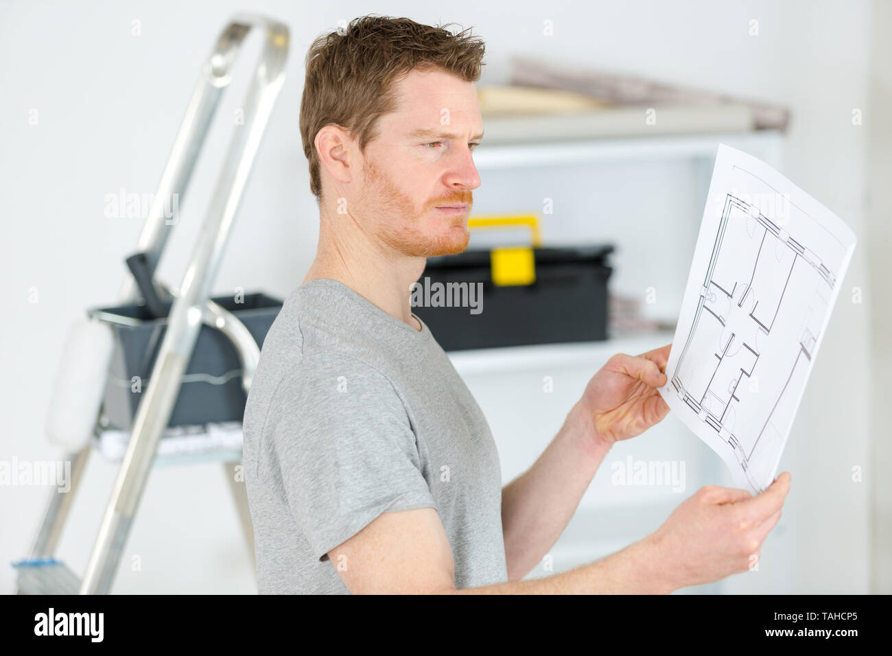 man lin room ooking at floorplan Stock Photo - Alamy