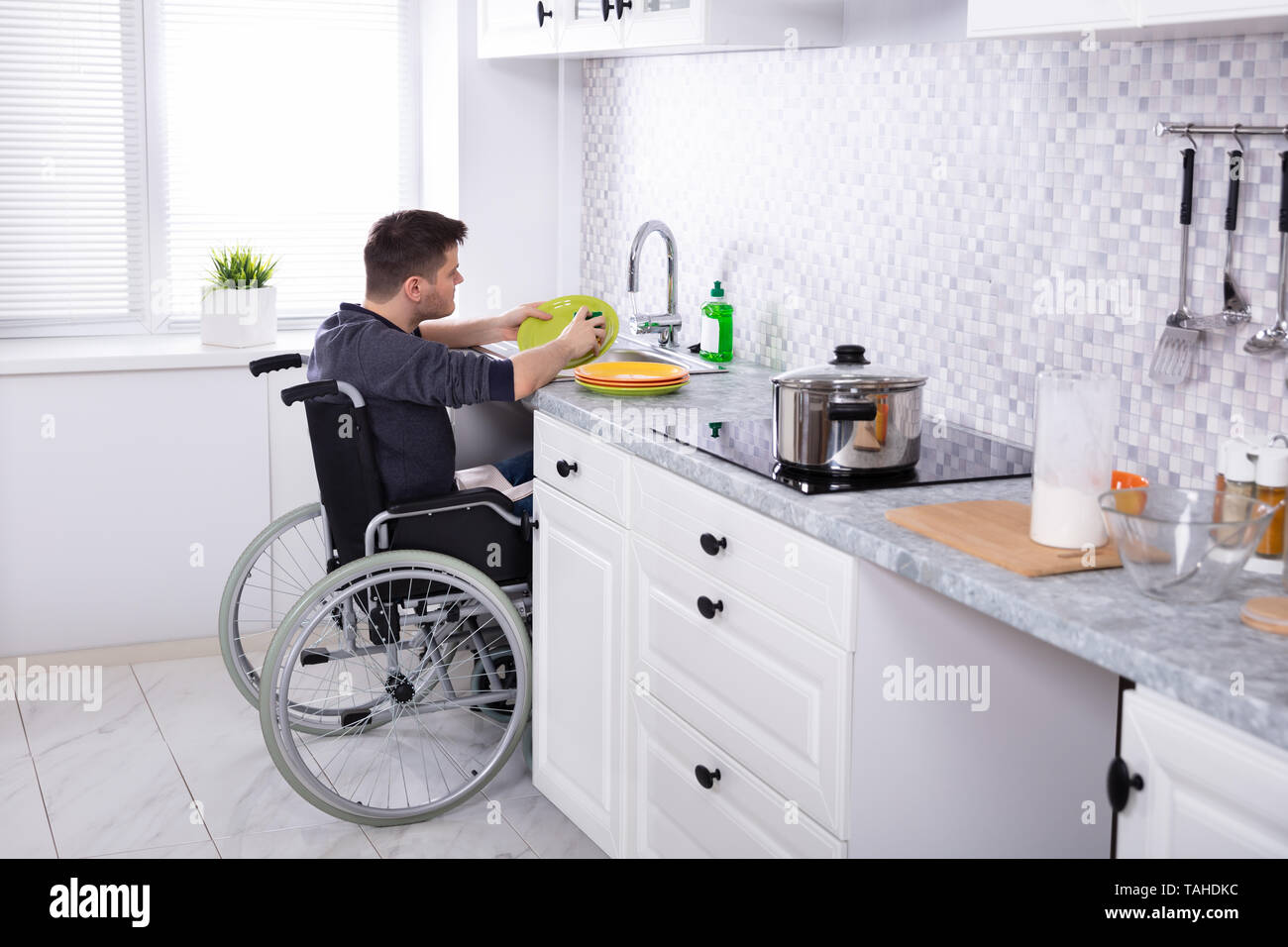 Handicapped Man Sitting On Wheelchair Washing And Cleaning Dishes In ...